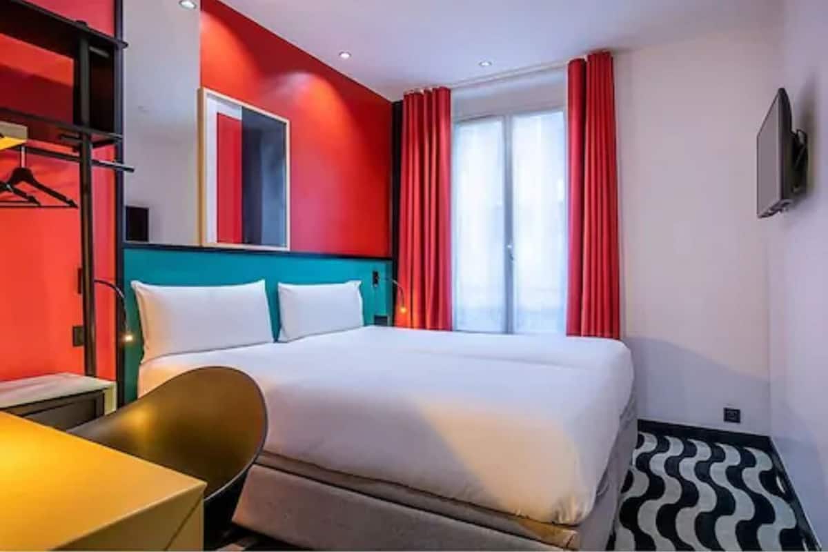 Quarto de hotel com cama, escrivaninha e cadeira.
