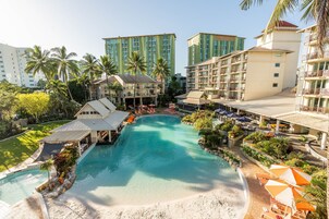 Um resort com uma piscina grande, vários edifícios e palmeiras.