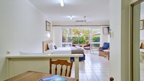 Quarto de hotel com uma cama, uma mesa de jantar e vista para o jardim pela janela.