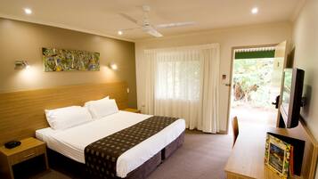 Quarto de hotel com cama, mesa de cabeceira e escrivaninha com um livro.