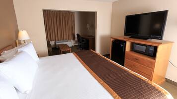 Quarto de hotel com uma cama grande, televisão, micro-ondas e escrivaninha com cadeira.