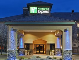Edifício Holiday Inn Express com fachada de pedra, entrada coberta e placa sobre a entrada.