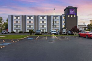 Um hotel Sleep Inn com estacionamento, várias vagas e céu claro.