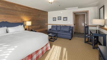 Quarto de hotel com uma cama grande, um sofá, uma escrivaninha e um espelho.