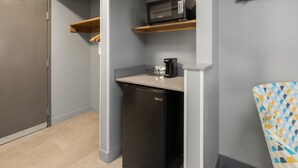 Uma cozinha compacta equipada com micro-ondas, cafeteira e máquina de lavar loiça.