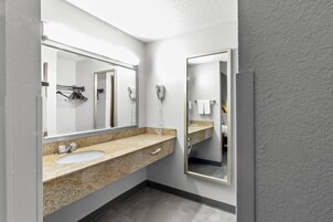 Uma casa de banho moderna com lavatório de bancada de granito, um espelho grande e um porta-toalhas.