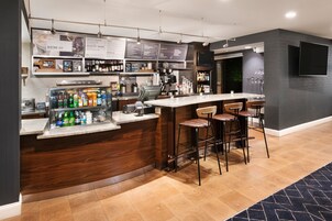 Um bistrô moderno com balcão, banquetas, máquina de café e quadro de cardápio.