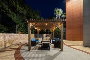 Uma área de estar ao ar livre com pérgola, assentos e um muro de pedra.
