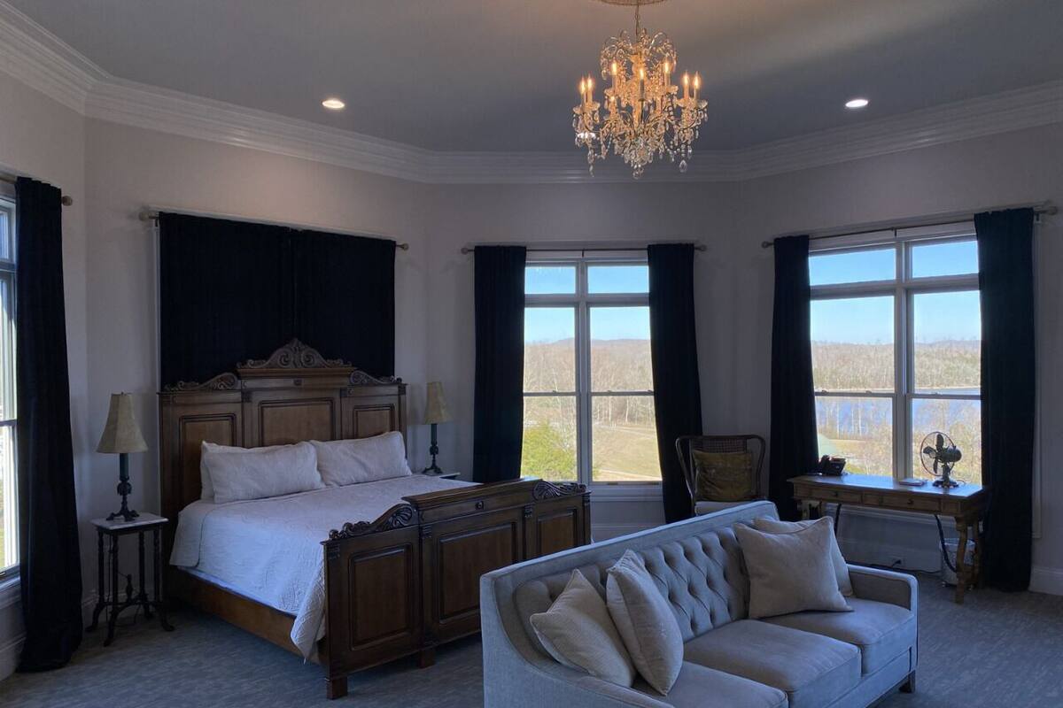 Quarto com uma cama grande, um sofá, uma escrivaninha e um candelabro.