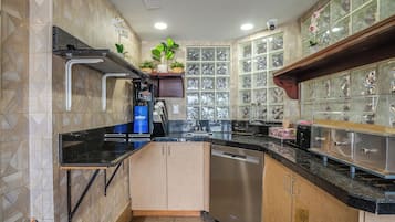 Uma cozinha com cafeteira, máquina de lavar louça e pia.