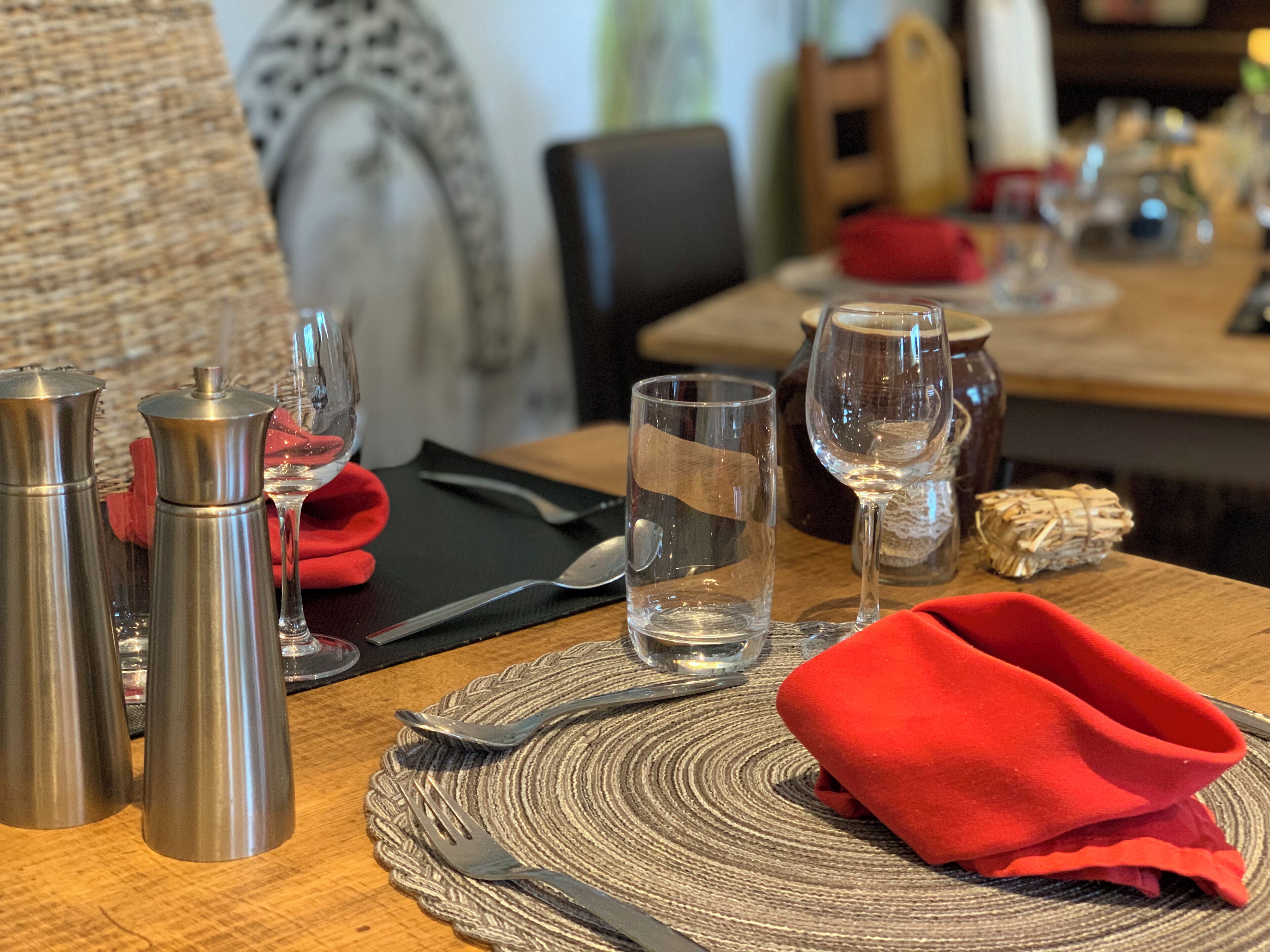 Mesa posta com talheres, copos e guardanapo vermelho.