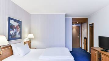 Quarto de hotel com uma cama grande, duas luminárias de cabeceira, uma televisão e um quadro pendurado na parede.