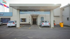 Entrada do Hotel e Centro de Conferências Abbots Hamilton, com dois carros estacionados na frente.
