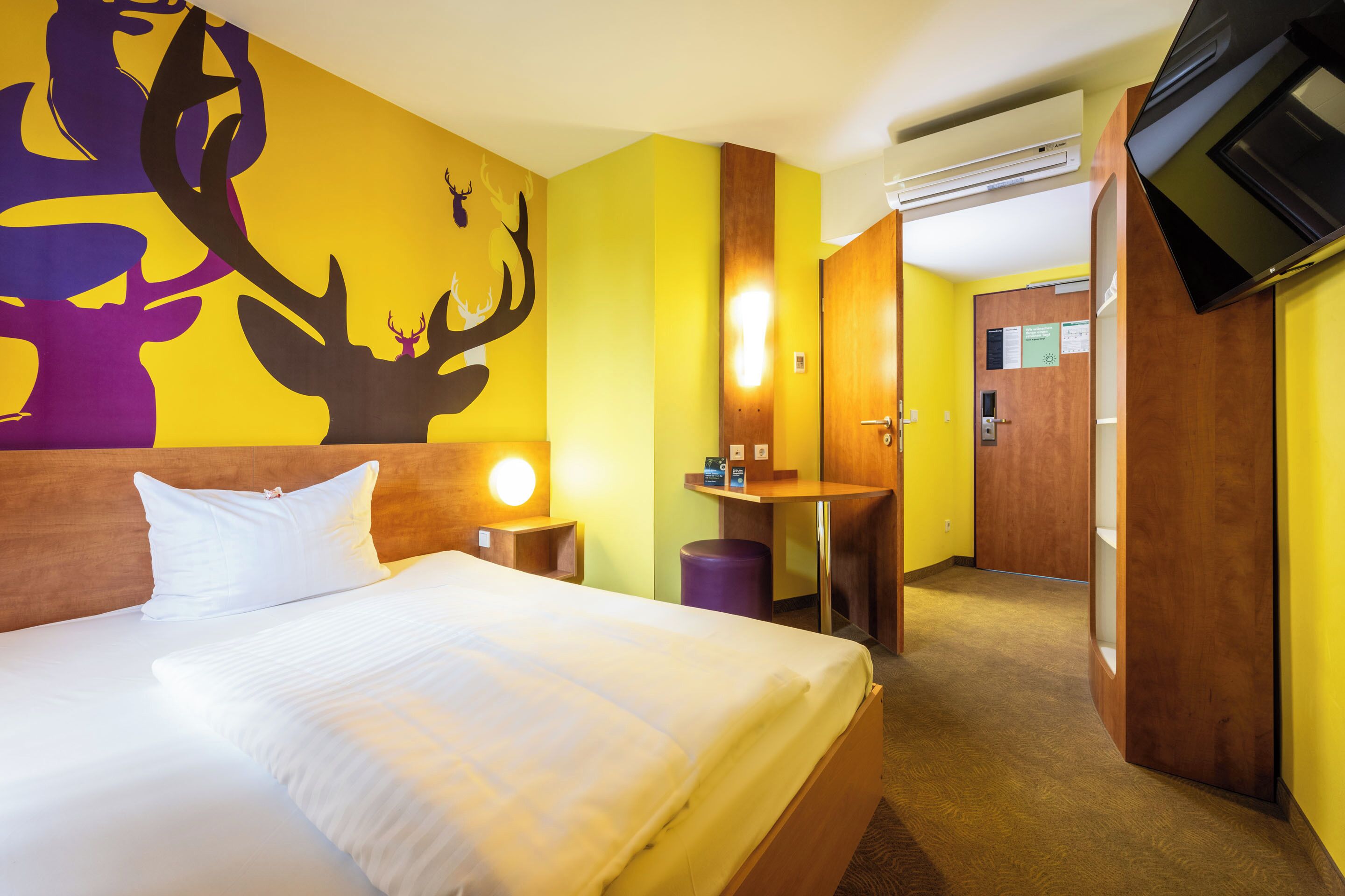 Quarto de hotel com uma cama grande, uma escrivaninha e um espelho.