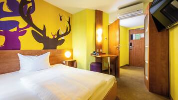 Quarto de hotel com uma cama grande, uma escrivaninha e um espelho.