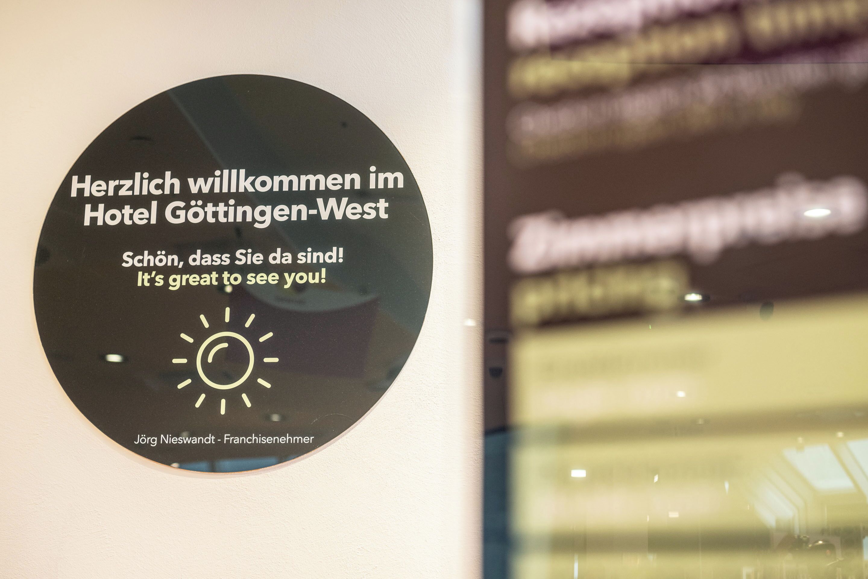 Placa de boas-vindas do Hotel Göttingen-West, com um ícone de sol e texto em alemão.