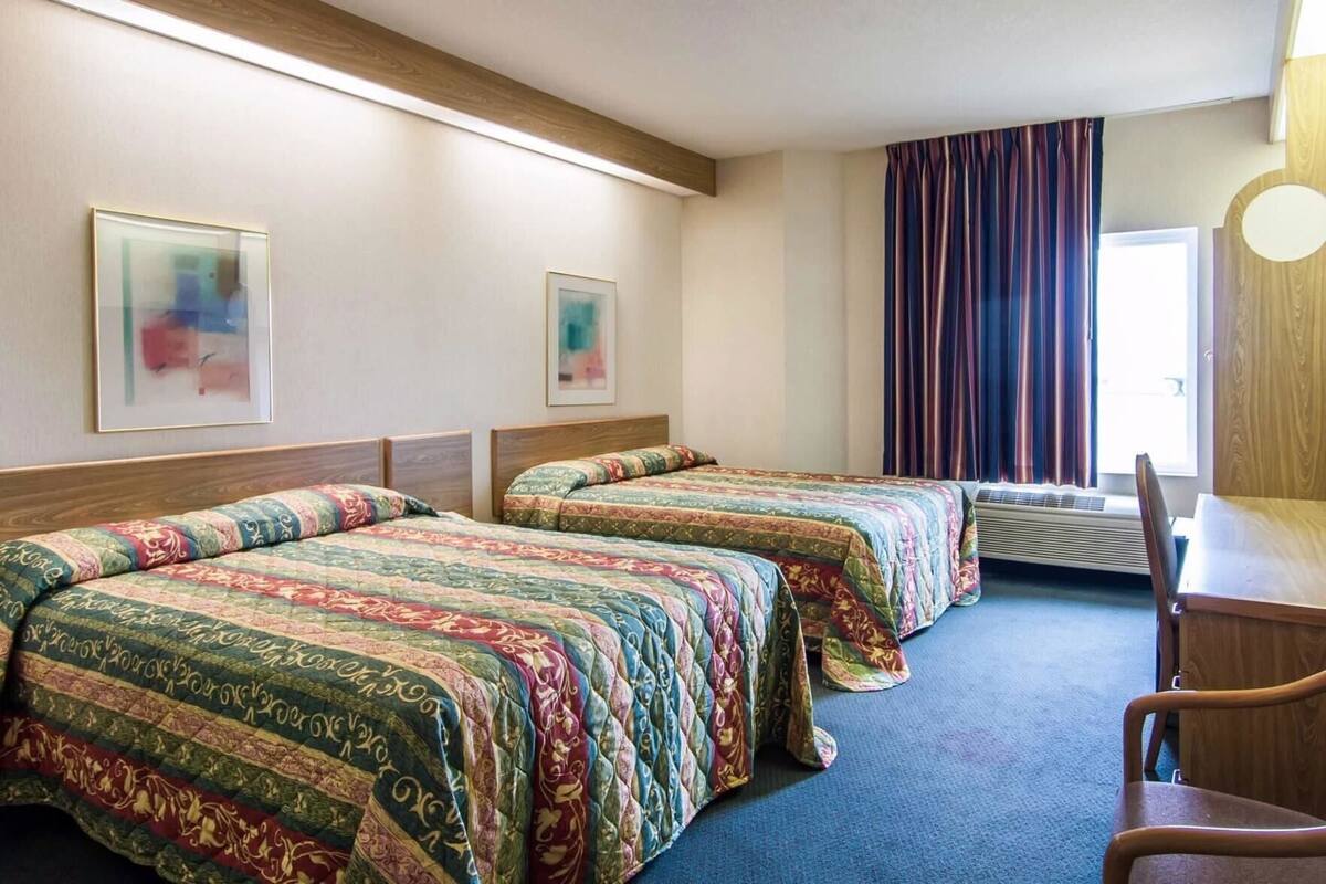 Quarto de hotel com duas camas, uma mesa e uma cadeira.
