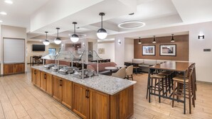 Uma cozinha moderna com bancadas de granito, armários de madeira e uma ilha central com equipamentos de preparação de alimentos.