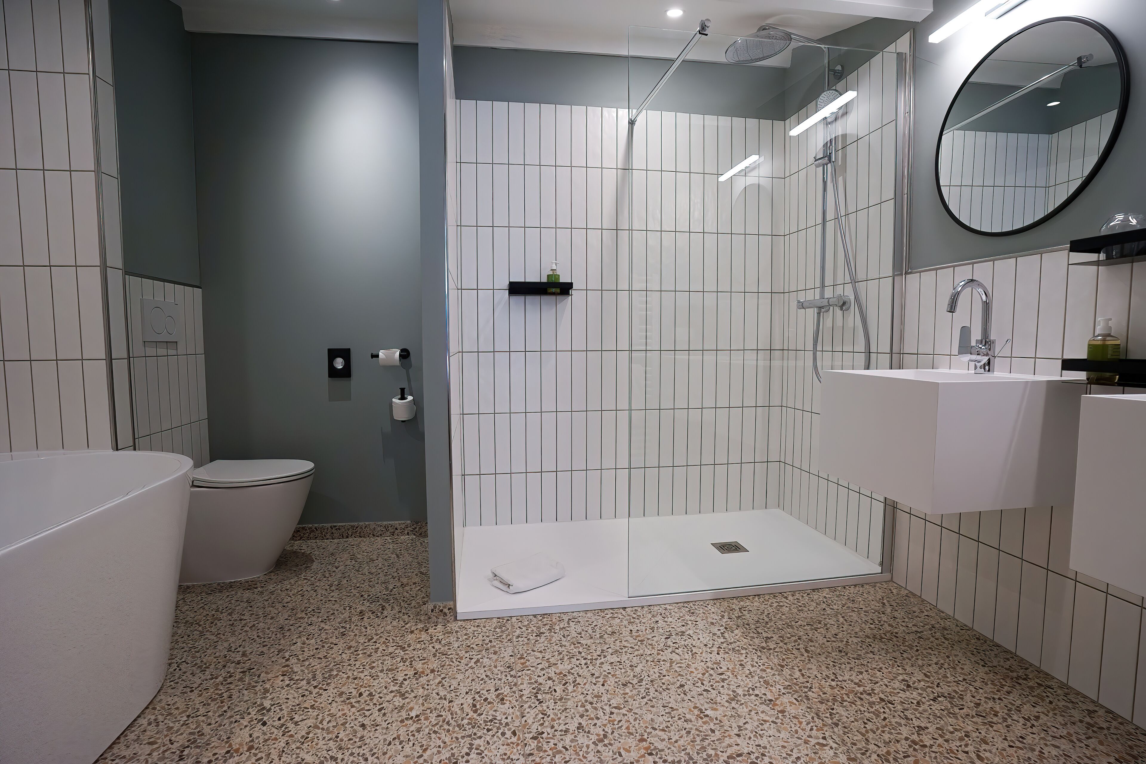 Uma casa de banho moderna com chuveiro, sanita e lavatório.