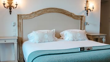 Quarto bem organizado com uma cama grande, mesas de cabeceira e um banquinho.