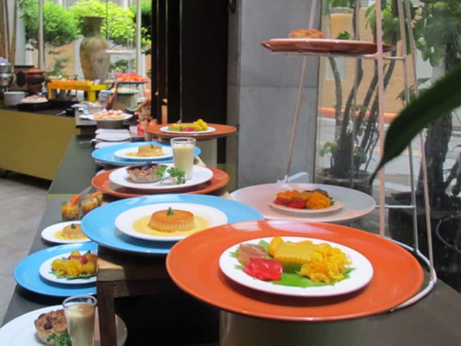 Disposição de buffet com diversos pratos, um canto de café e um vaso decorativo.