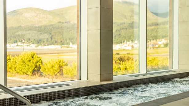 Área de spa com hidromassagem e vista para vinhedos e montanhas.