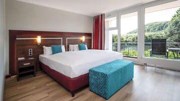 Quarto de hotel moderno com uma cama grande, cabeceira de madeira e uma varanda com vista panorâmica.