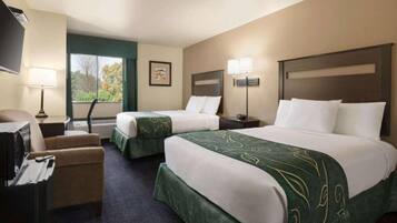 Quarto de hotel com duas camas, uma escrivaninha, uma cadeira e uma televisão.