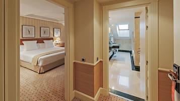 Quarto de hotel com cama, mesa de cabeceira, abajur e quadros na parede.