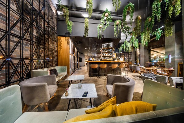 Um interior moderno com áreas de estar, plantas pendentes e um bar.