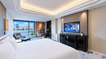 Quarto de hotel moderno com uma cama grande, televisão, vista para a cidade e varanda.