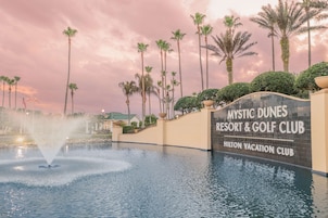 Uma fonte em área de piscina, com palmeiras e um aviso para Mystic Dunes Resort & Golf Club.