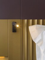 Quarto moderno com luminária fixada na parede e cortina branca.