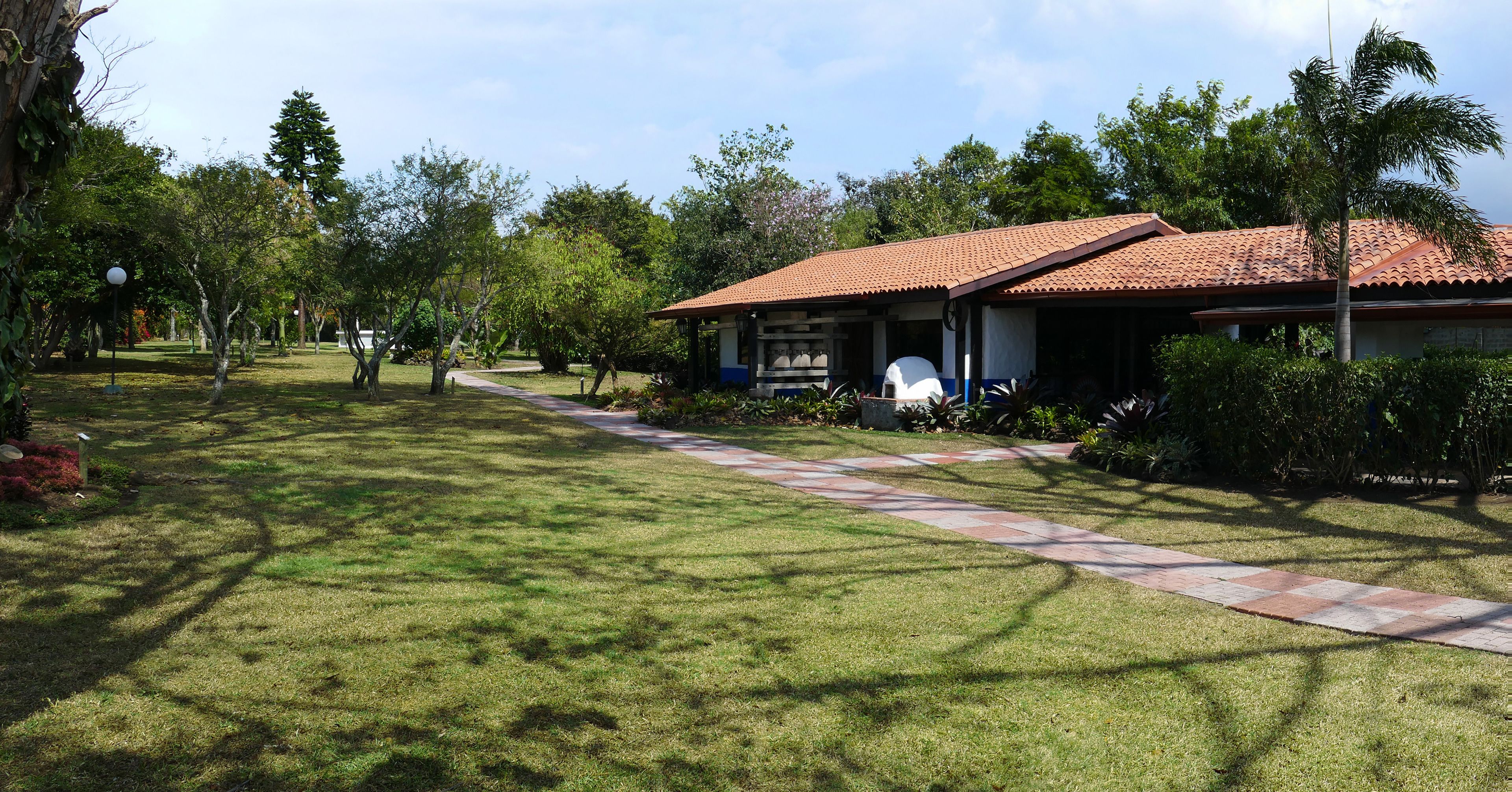 Uma casa com telhado de cerâmica, rodeada por um gramado bem cuidado e árvores.
