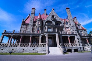 Um grande edifício de pedra histórico, com entrada imponente, várias chaminés e telhado vermelho.