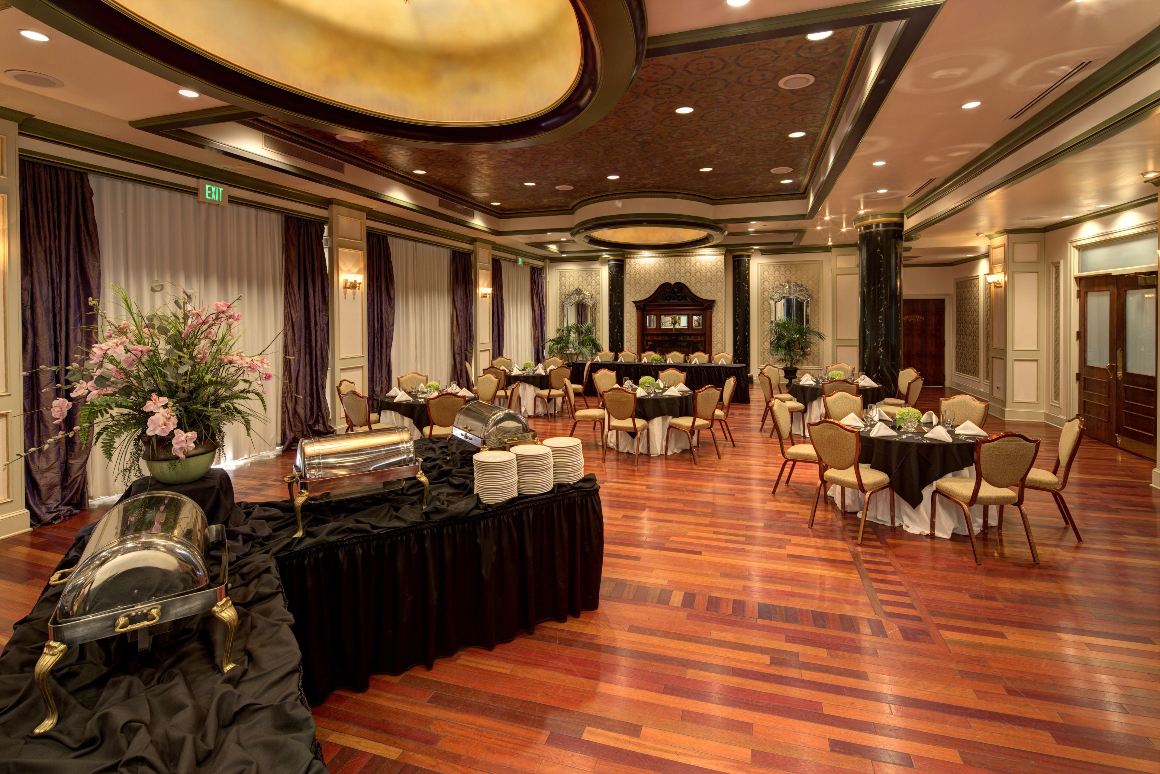 Uma sala de banquetes com várias mesas redondas, cadeiras e um buffet.