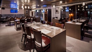 Um restaurante com várias mesas, cadeiras e um espaço de bar.