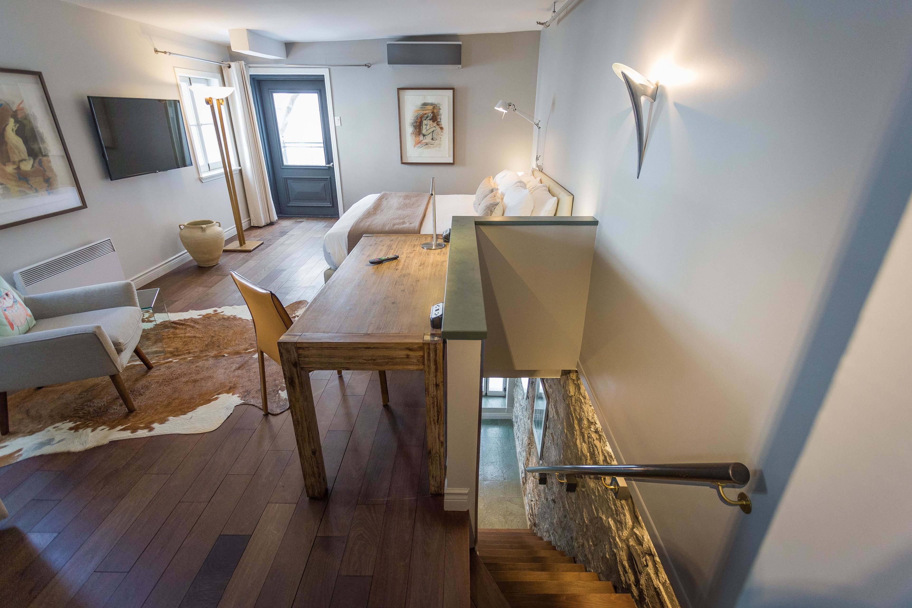 Uma sala de estar moderna com uma mesa de jantar de madeira, um sofá e uma escada que leva a um andar superior.