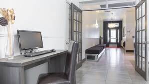 Um espaço de escritório moderno com uma mesa, cadeira, computador e um vaso de flores secas.
