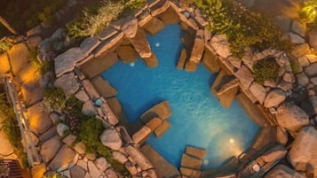 Piscina circular rodeada por pedras e plantas.