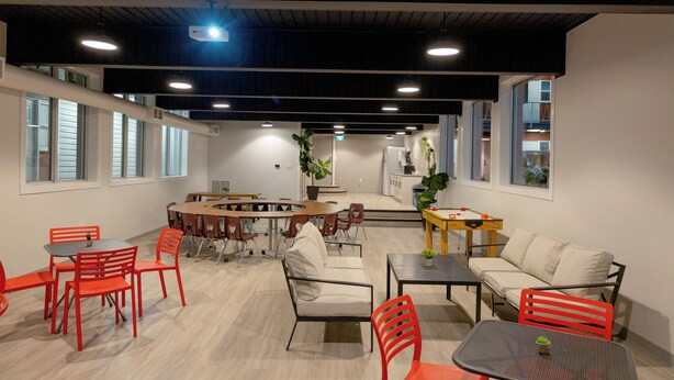 Decoração moderna com área de refeições, assentos e cozinha ao fundo.