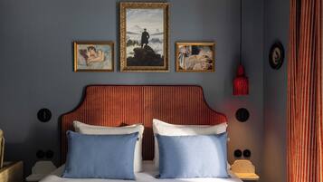 Quarto de hotel com cama grande, duas almofadas, cabeceira e três obras de arte emolduradas na parede.