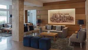 Um lobby moderno com um grande mural, assentos confortáveis e um chão limpo e lustroso.