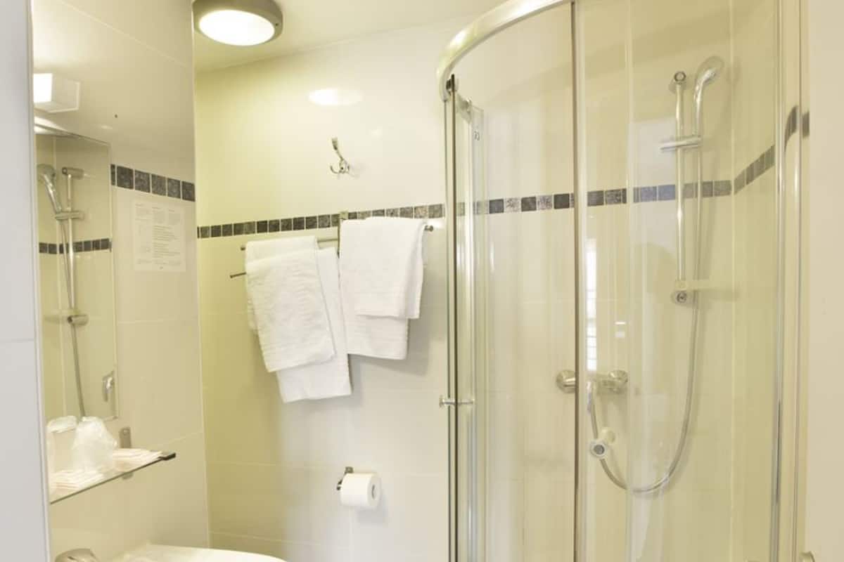 Um banheiro moderno com chuveiro em box de vidro, pia branca e piso revestido com azulejos.