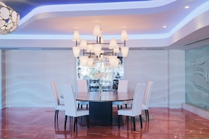 Uma sala de jantar moderna com uma mesa redonda, cadeiras brancas e um lustre exclusivo.