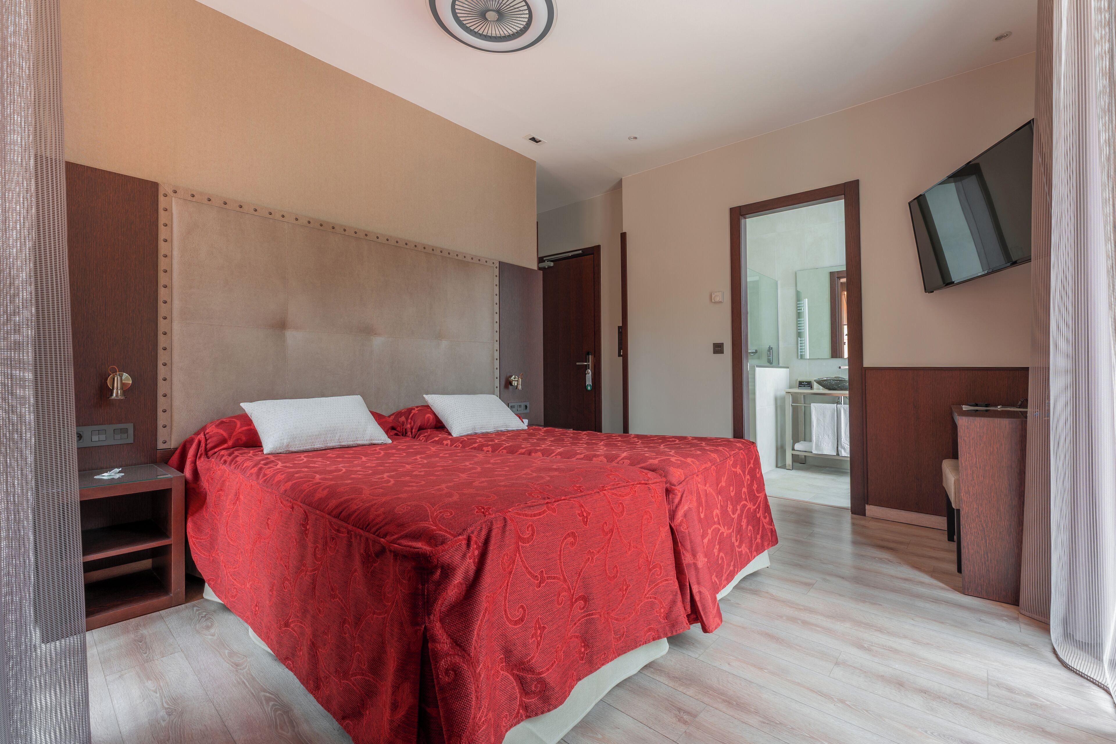 Quarto de hotel com uma cama grande, uma televisão fixada na parede e uma porta que dá para um banheiro.