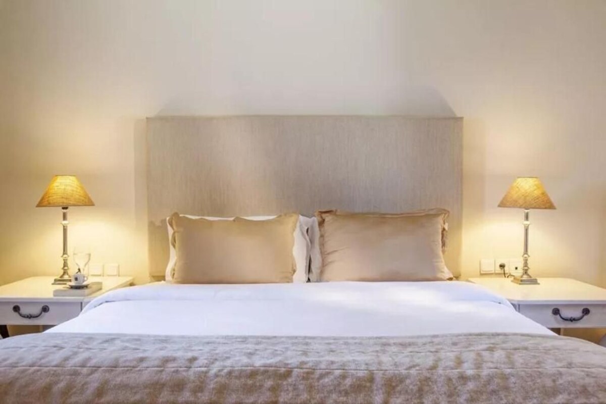 Quarto de hotel com uma cama grande, duas mesas de cabeceira e luminárias.
