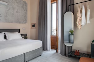 Quarto moderno com uma cama grande, um espelho e um banco com sapatos.