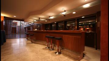 Uma área de bar com um balcão comprido e quatro banquetas.