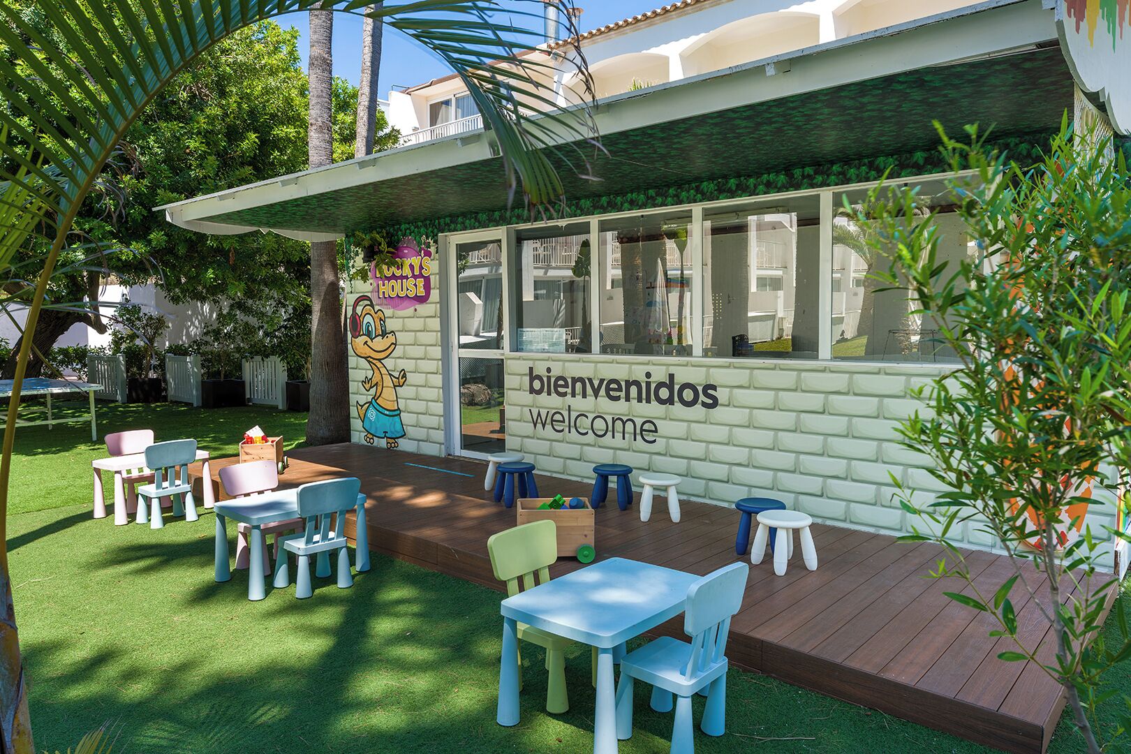 Uma área de recreação infantil com uma placa que diz 'bienvenidos welcome' e um personagem de desenho animado.